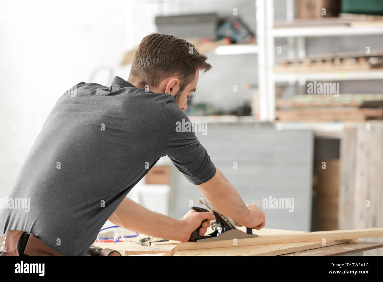 Carpenter planing timber in light workshop Stock Photo - Alamy
