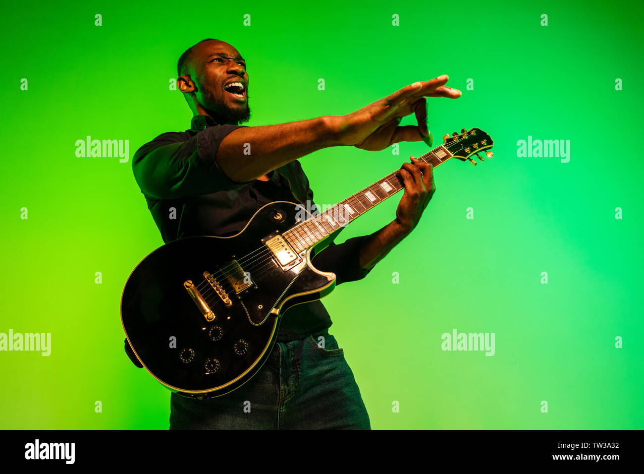 Young african-american musician playing the guitar like a rockstar on ...