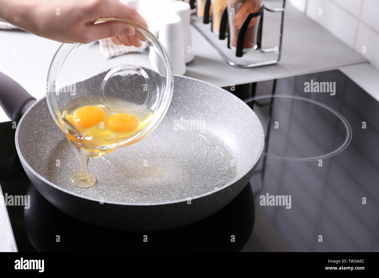 Woman pouring eggs from bowl into frying pan Stock Photo - Alamy