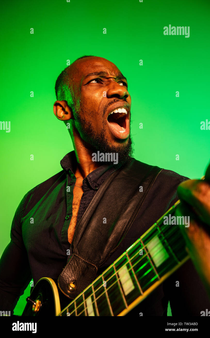 Young african-american musician playing the guitar like a rockstar on ...