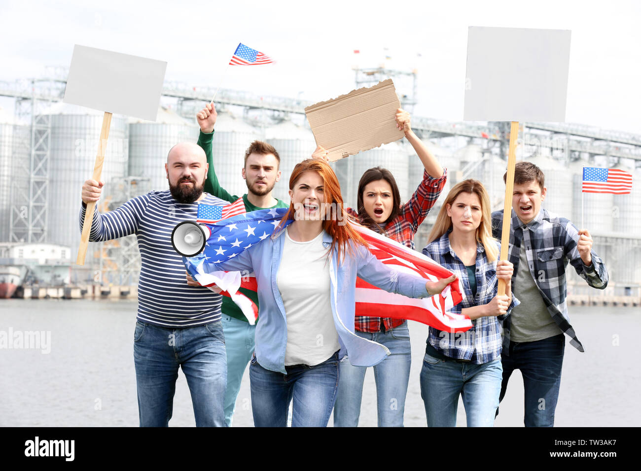 Group of protesting young people with American flag and factory on ...