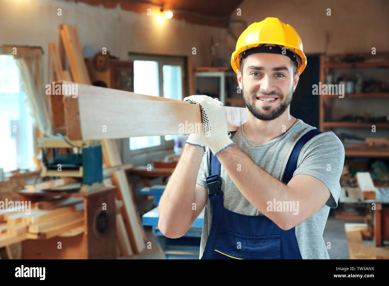Handsome young carpenter with boards in workshop Stock Photo - Alamy
