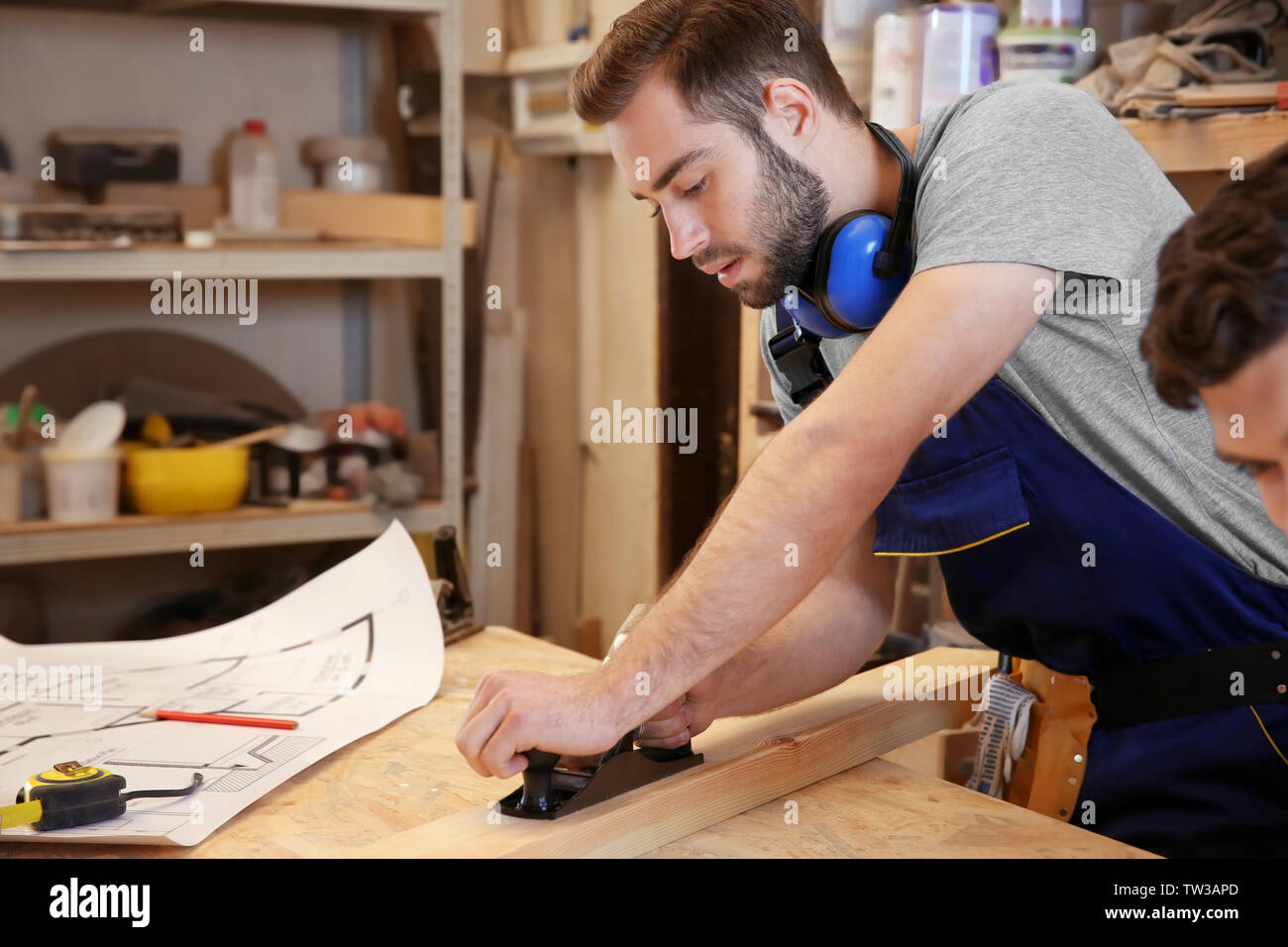 Young carpenter planing timber in workshop Stock Photo - Alamy