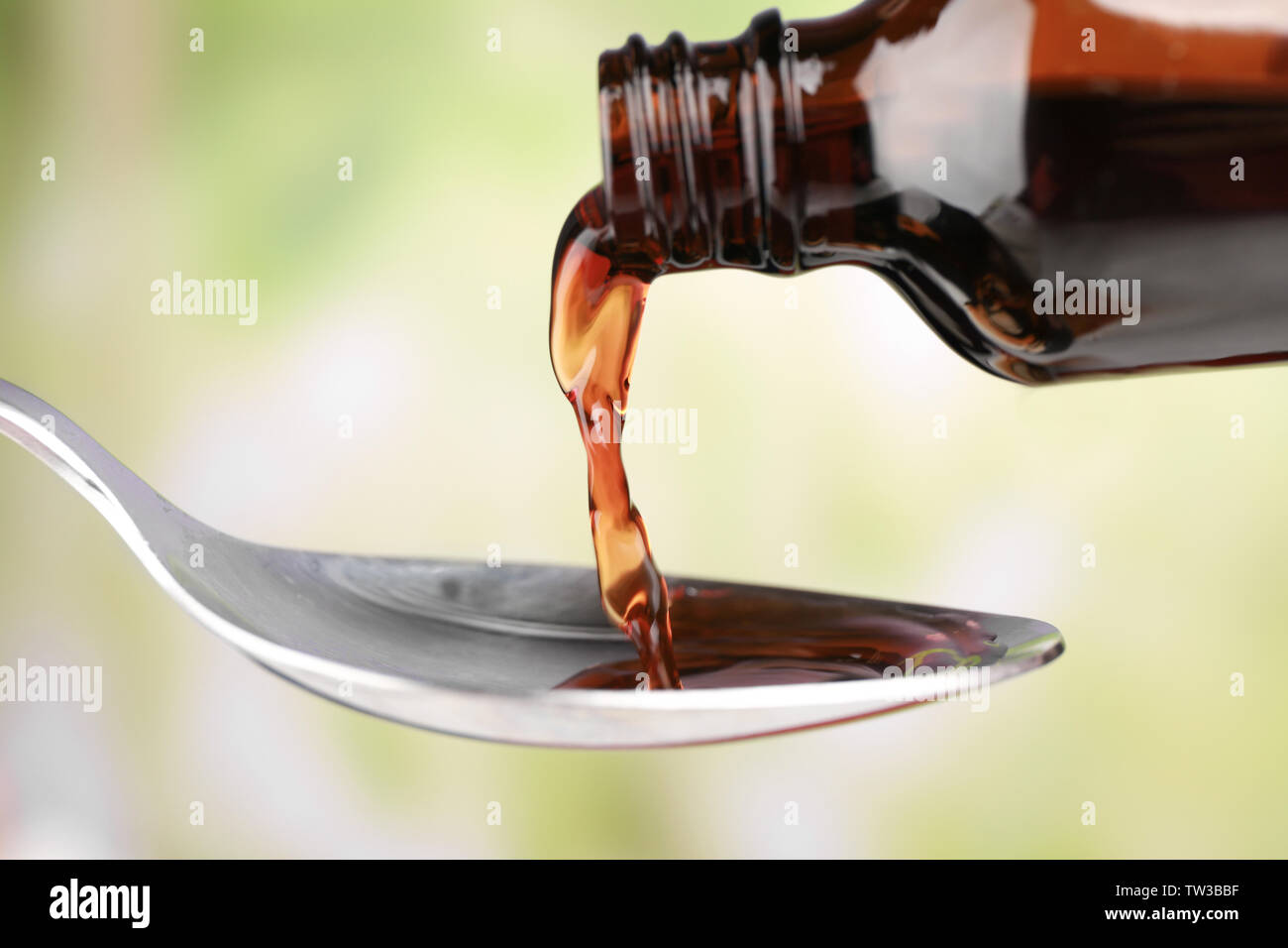 Pouring cough syrup into spoon on blurred background Stock Photo - Alamy