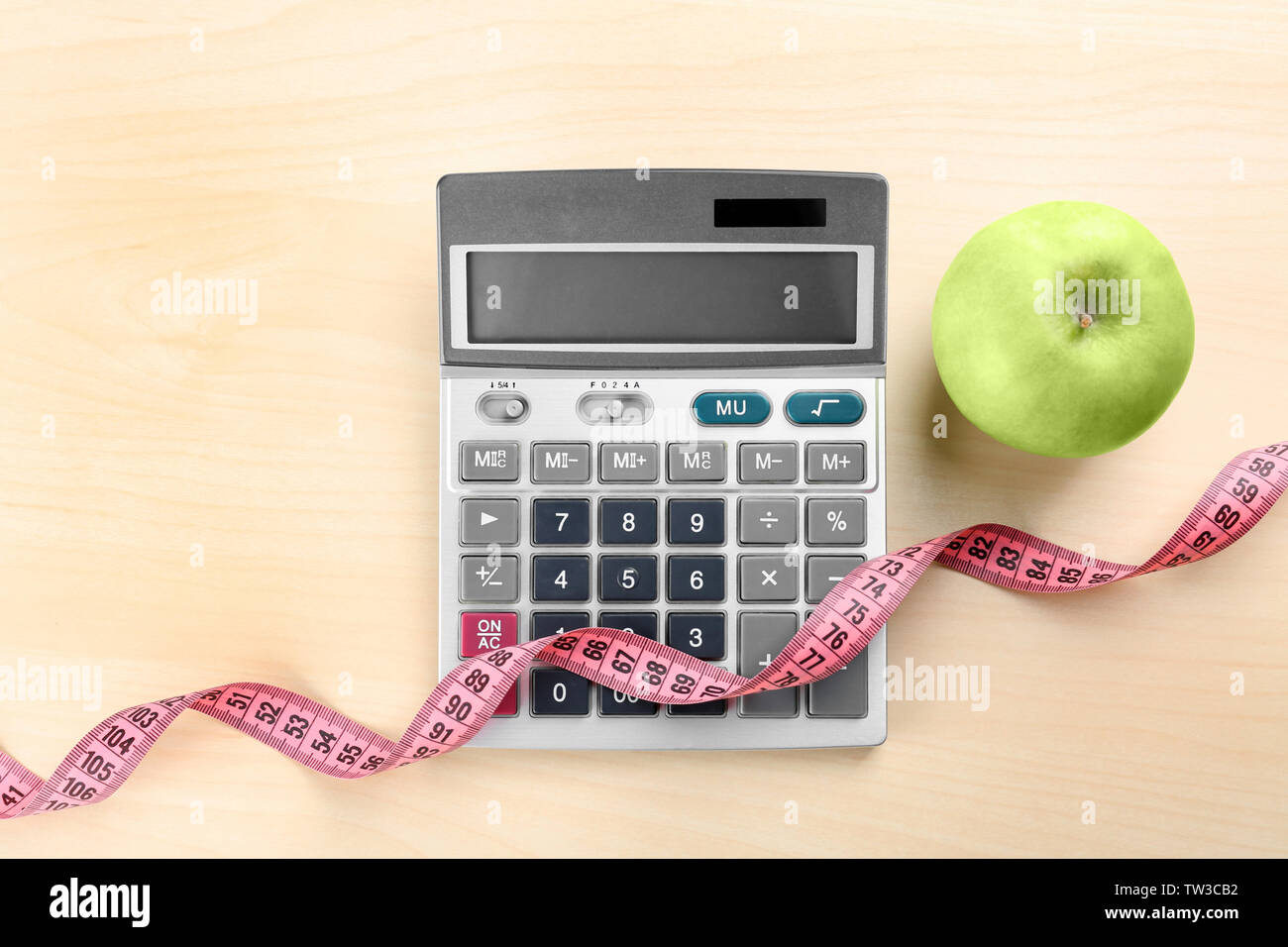 Weight loss concept. Apple, calculator and measuring tape on light ...