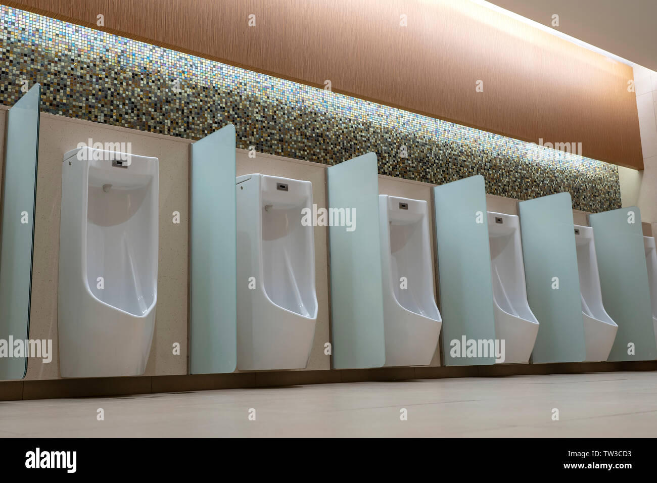 A row of white urinals in tiled wall in a public restroom. Empty man ...