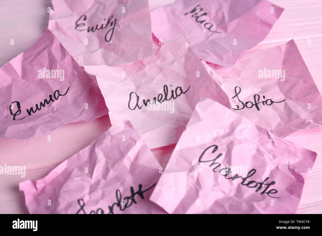 Crumpled paper stickers with different names on color wooden background ...