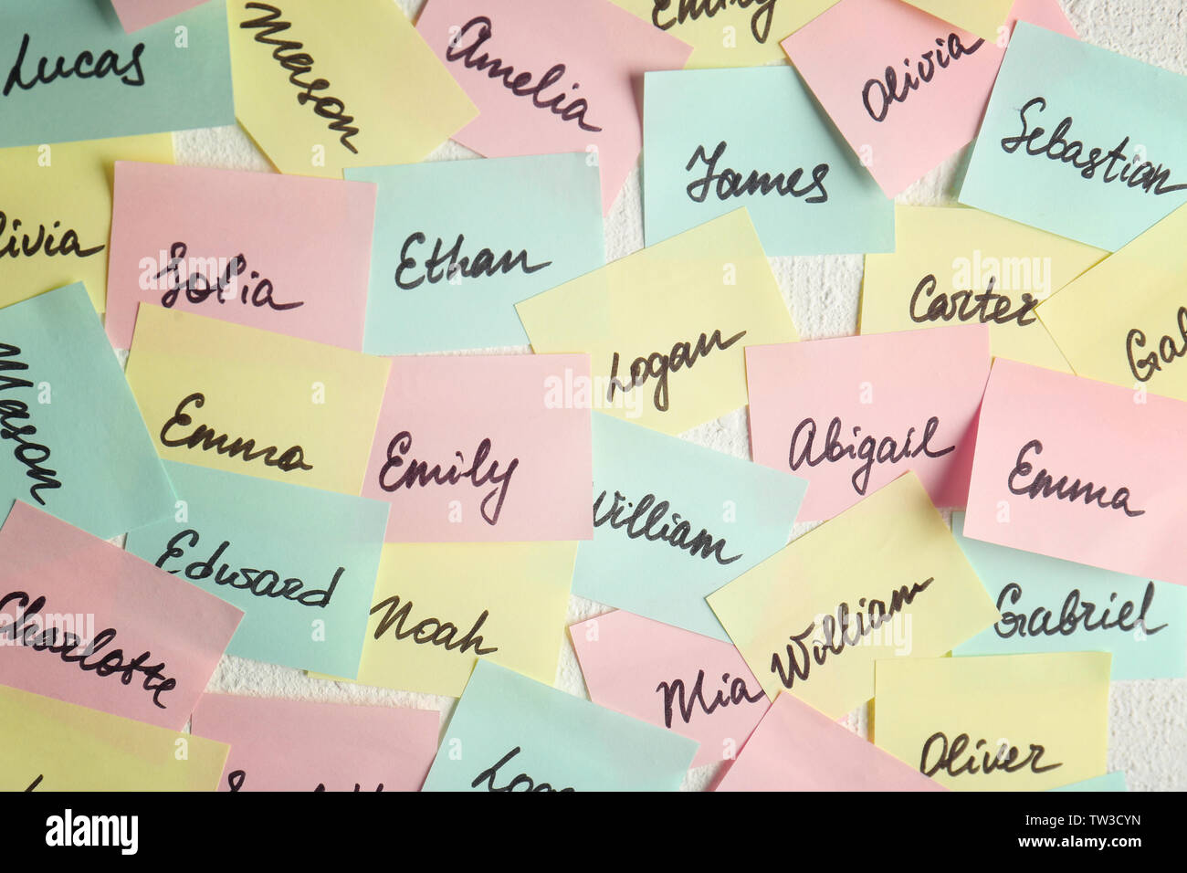 Closeup of paper stickers with different names on white wall. Concept ...
