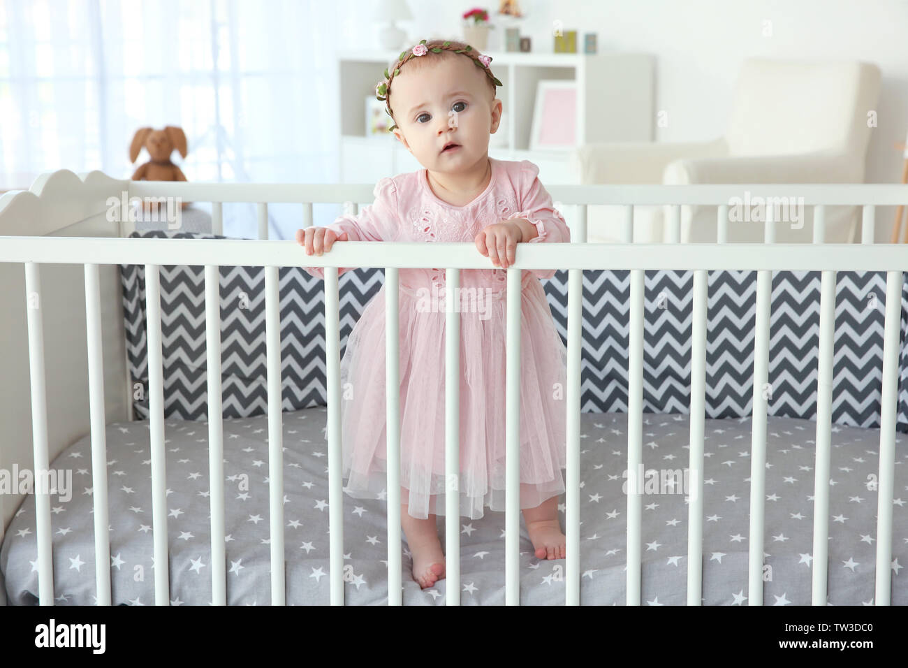 Cute little girl standing in crib at home Stock Photo - Alamy