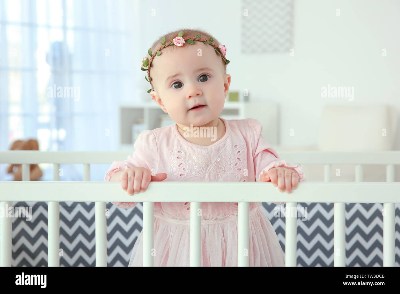 Cute little girl standing in crib at home Stock Photo - Alamy
