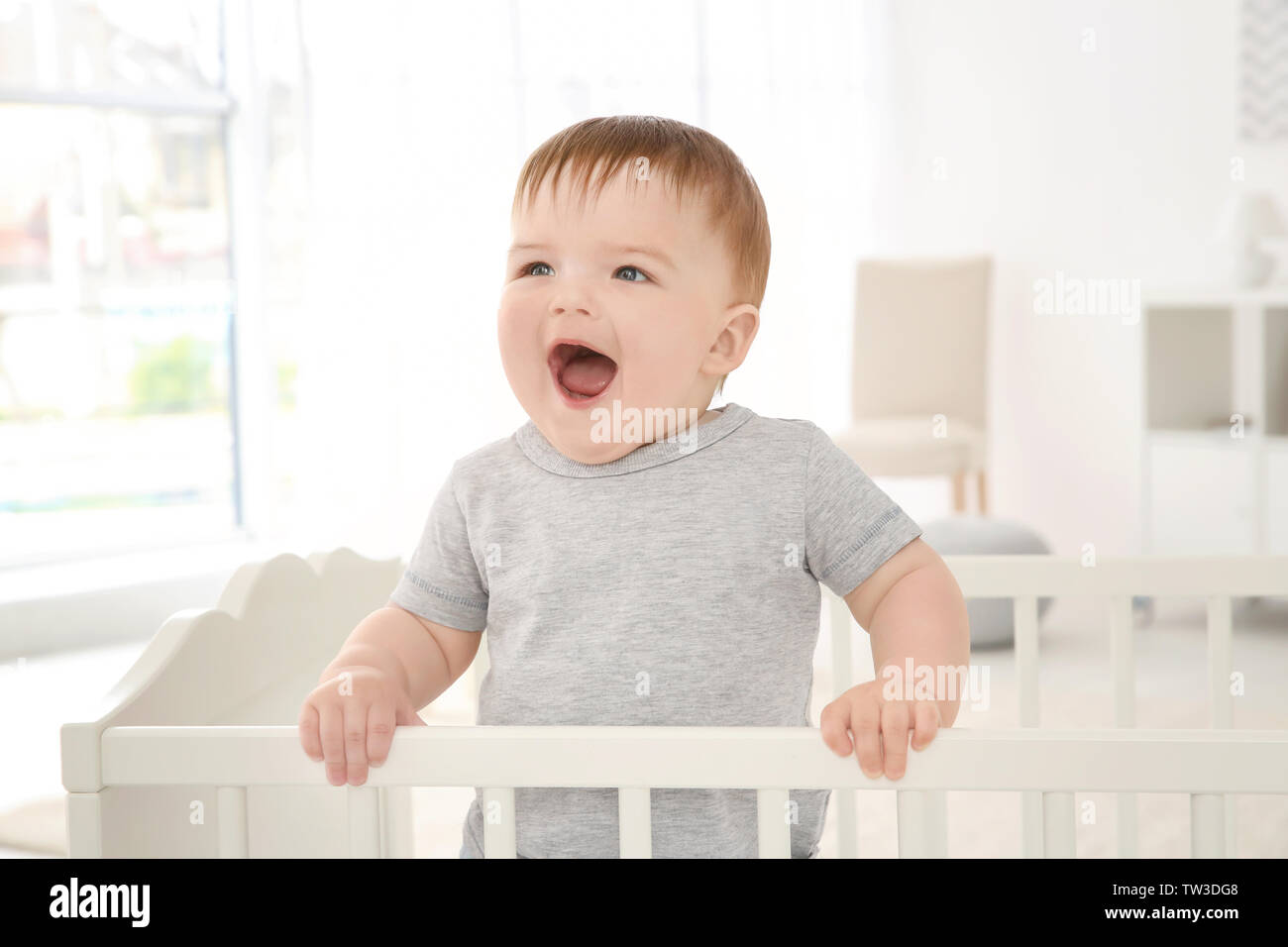 Cute little baby standing in crib at home Stock Photo - Alamy