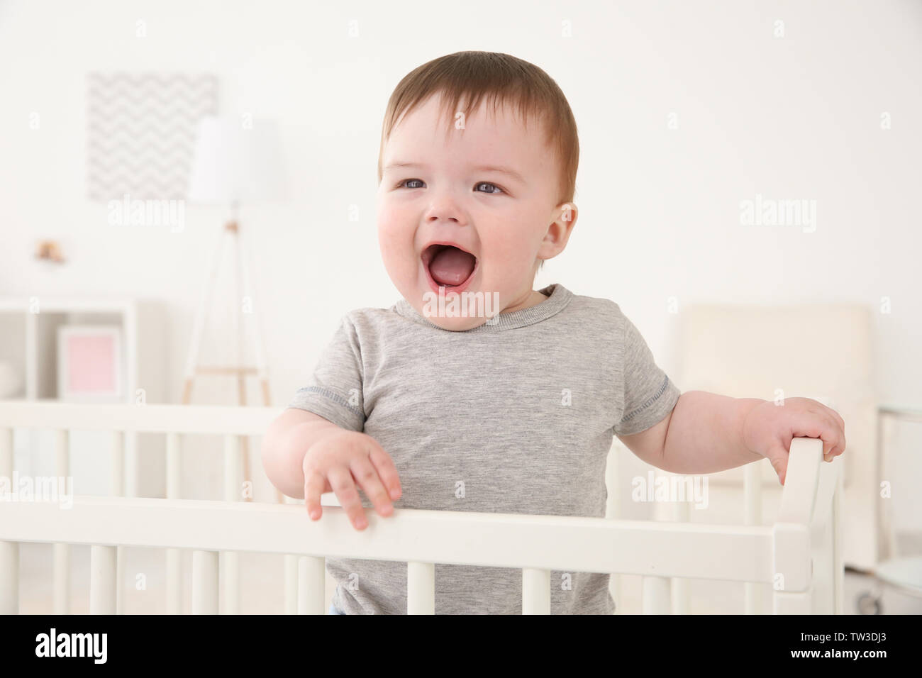 Cute little baby standing in crib at home Stock Photo - Alamy