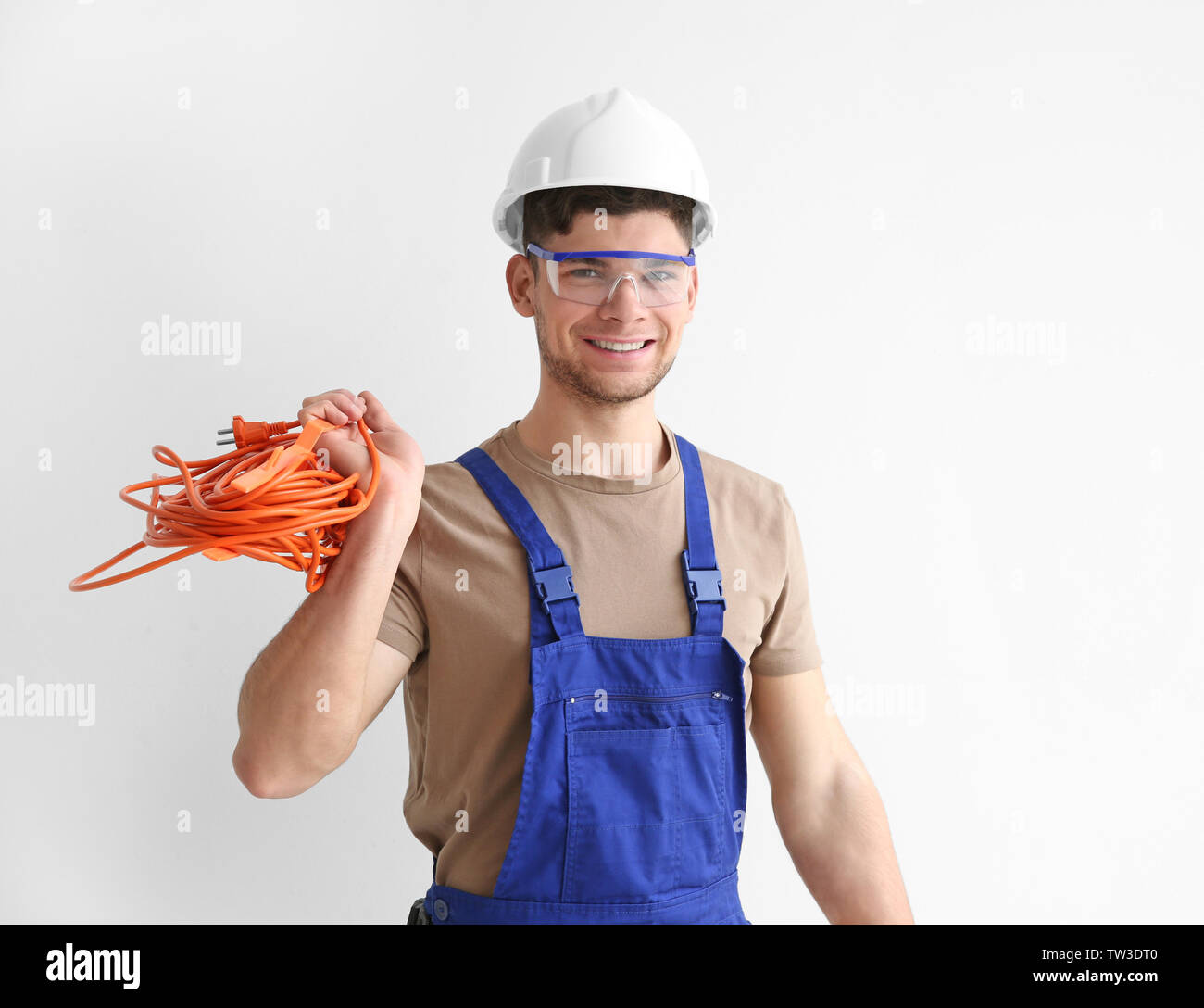 Young smiling electrician with bunch of wires on white background Stock ...