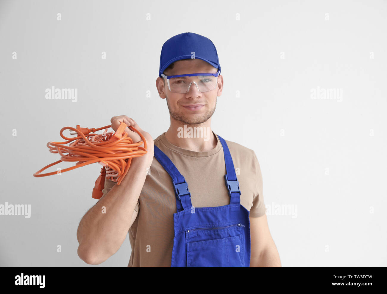 Young smiling electrician with bunch of wires on white background Stock ...