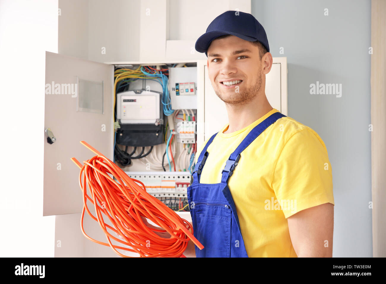 Young smiling electrician with bunch of wires standing near ...