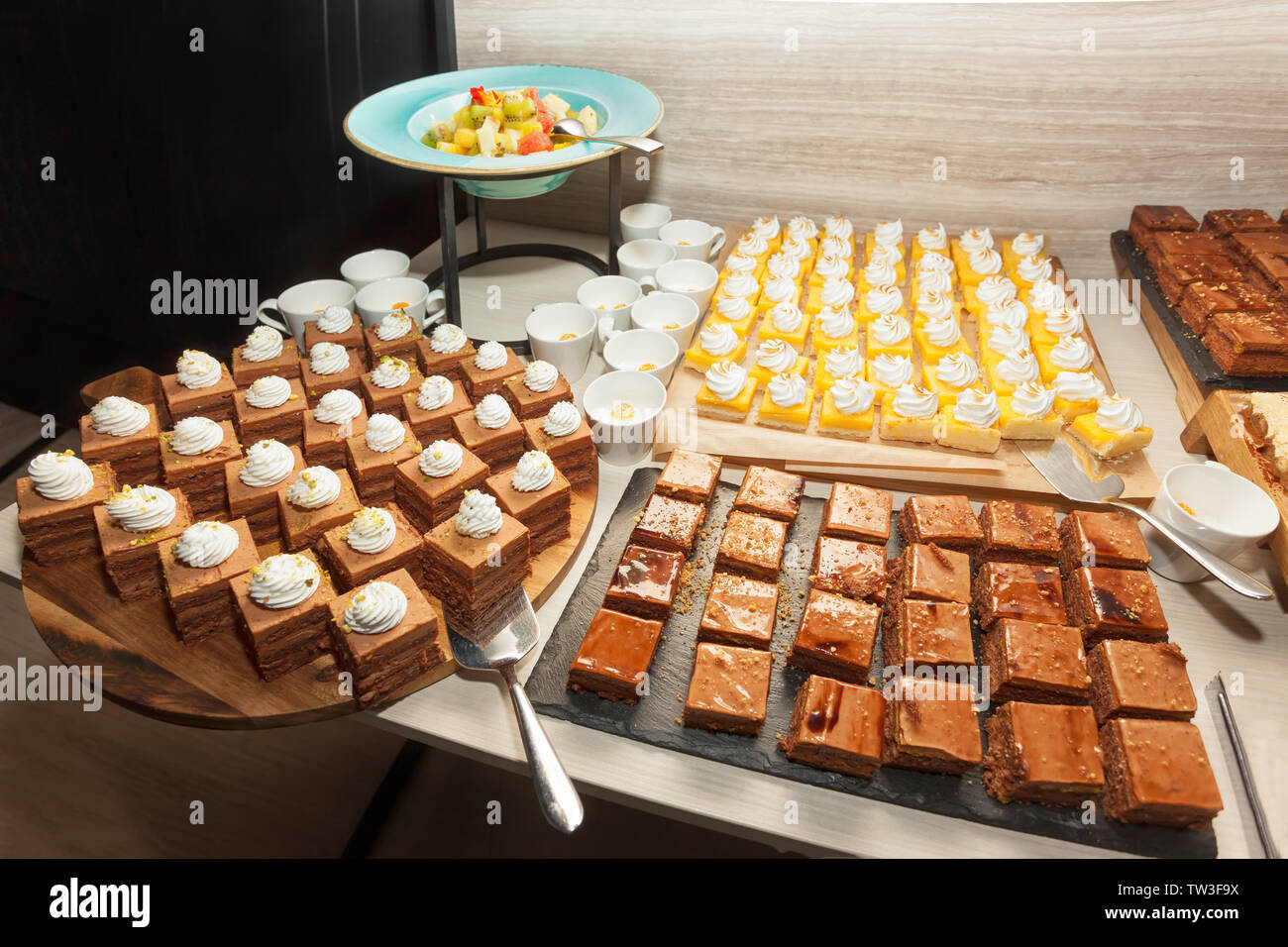 Small assorted cakes lined up decorated on dessert buffet along with ...