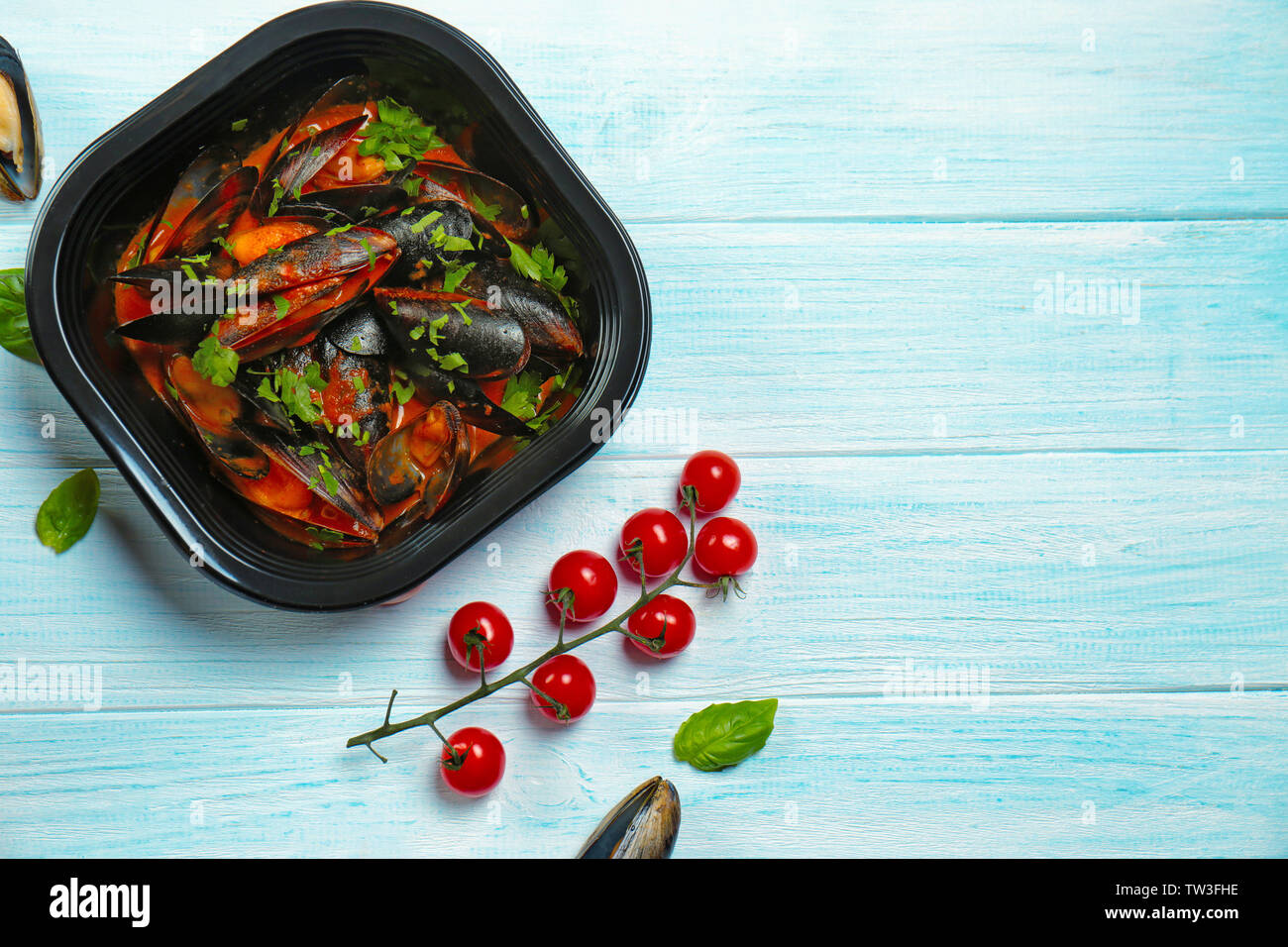 Plastic container with delicious mussels in tomato sauce on wooden ...