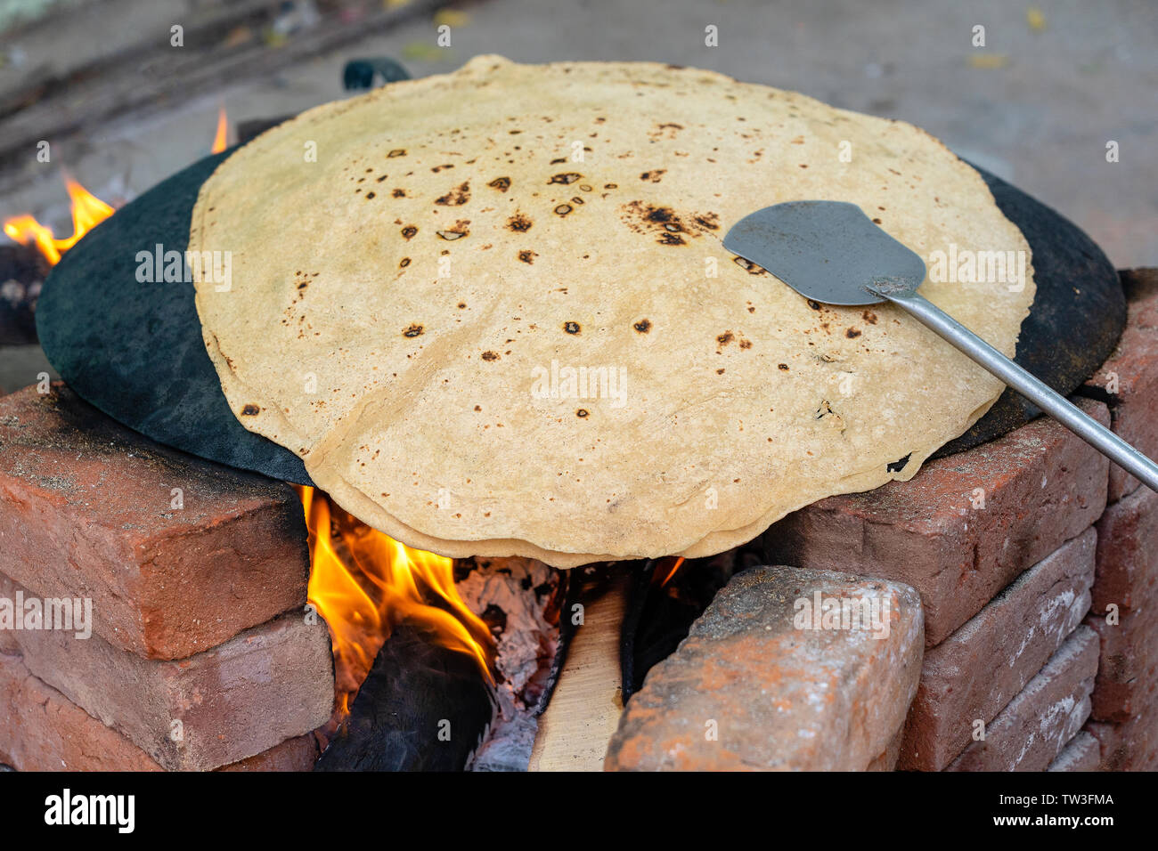 Indian woman cooking traditional indian bread, big chapati cooking on ...