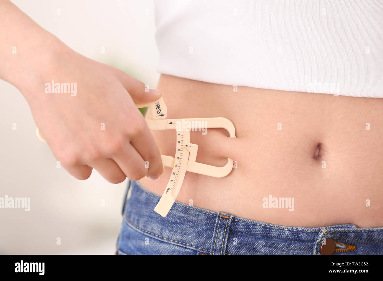 Young woman with measuring caliper on light background, closeup. Weight ...