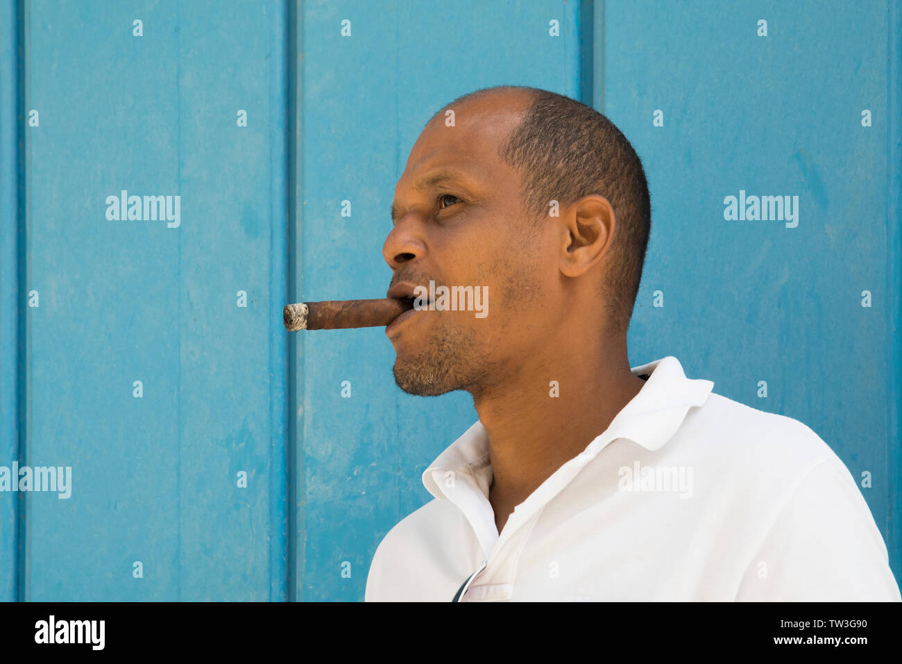 A Cuban man smoking a cigar on the streets of Havana Cuba. Infront of ...
