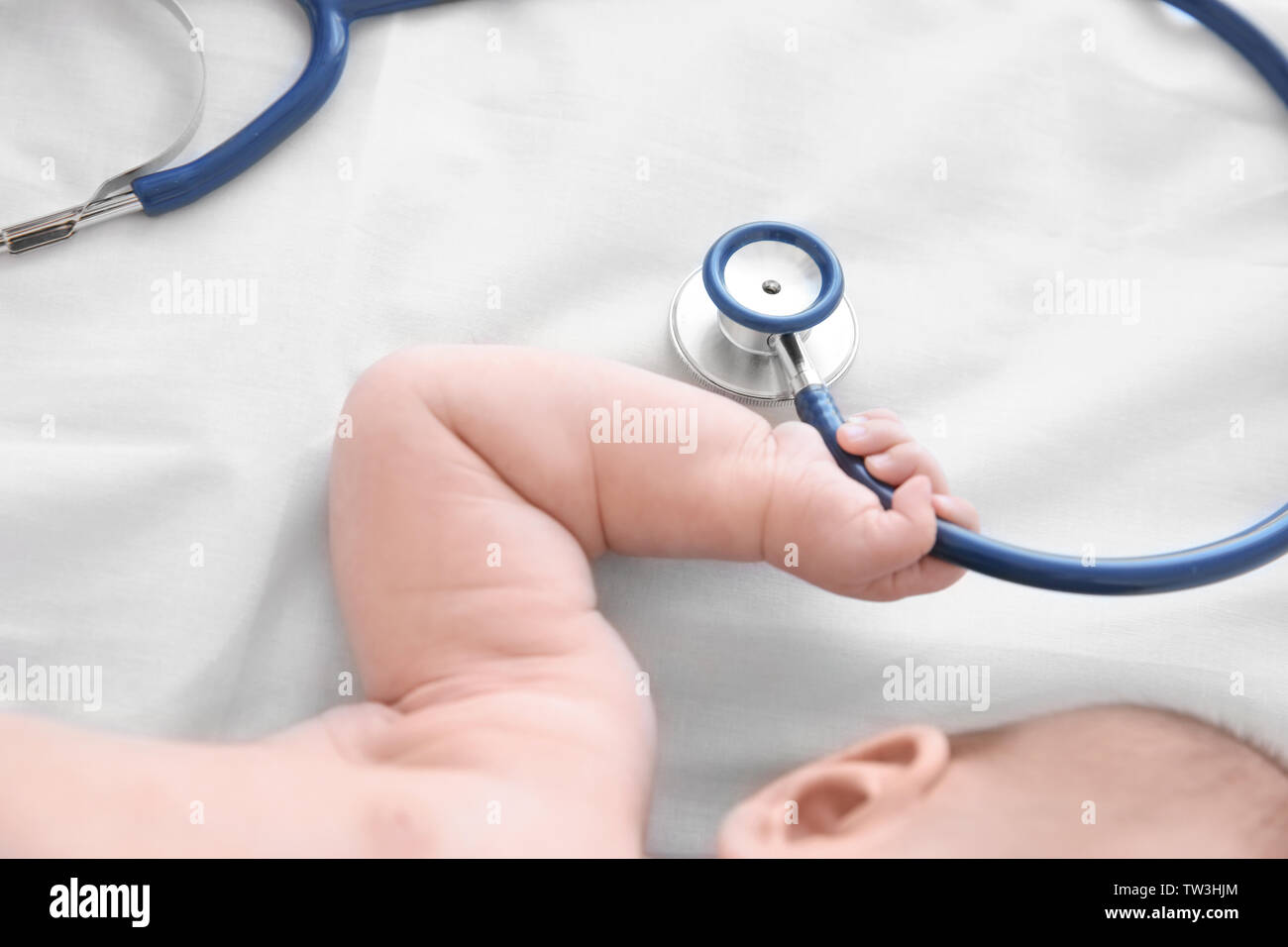 Cute baby with stethoscope lying on bedsheet. Baby health concept Stock ...