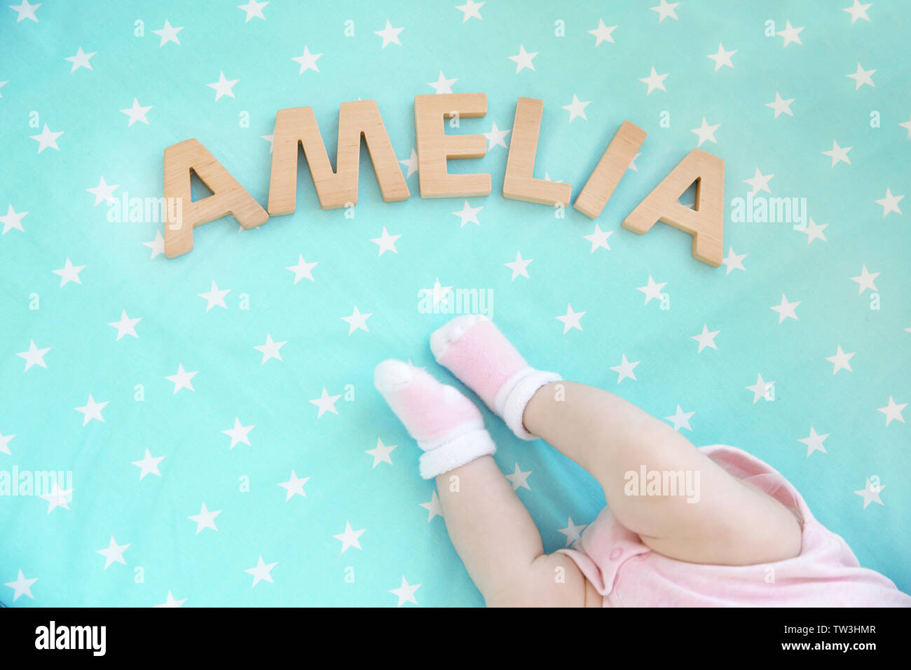 Legs of cute baby and word AMELIA composed of wooden letters on bed ...