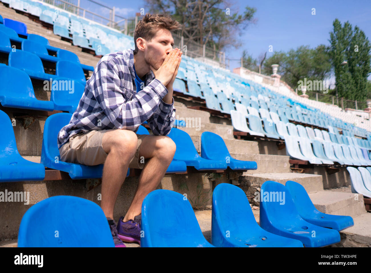 portrait of young emotional male sitting on the sport stadium during ...