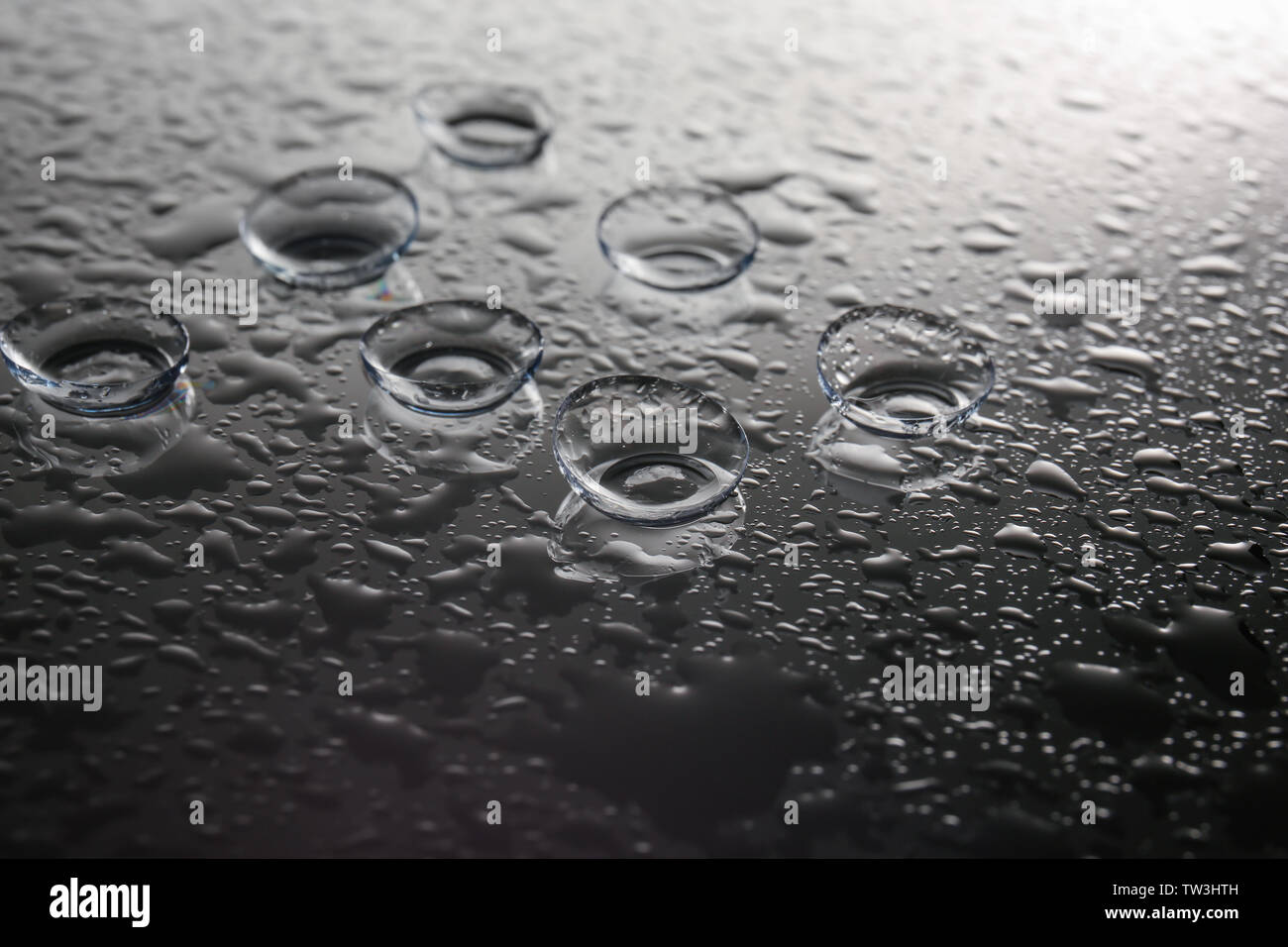 Contact lenses and drops of water on gray background Stock Photo - Alamy