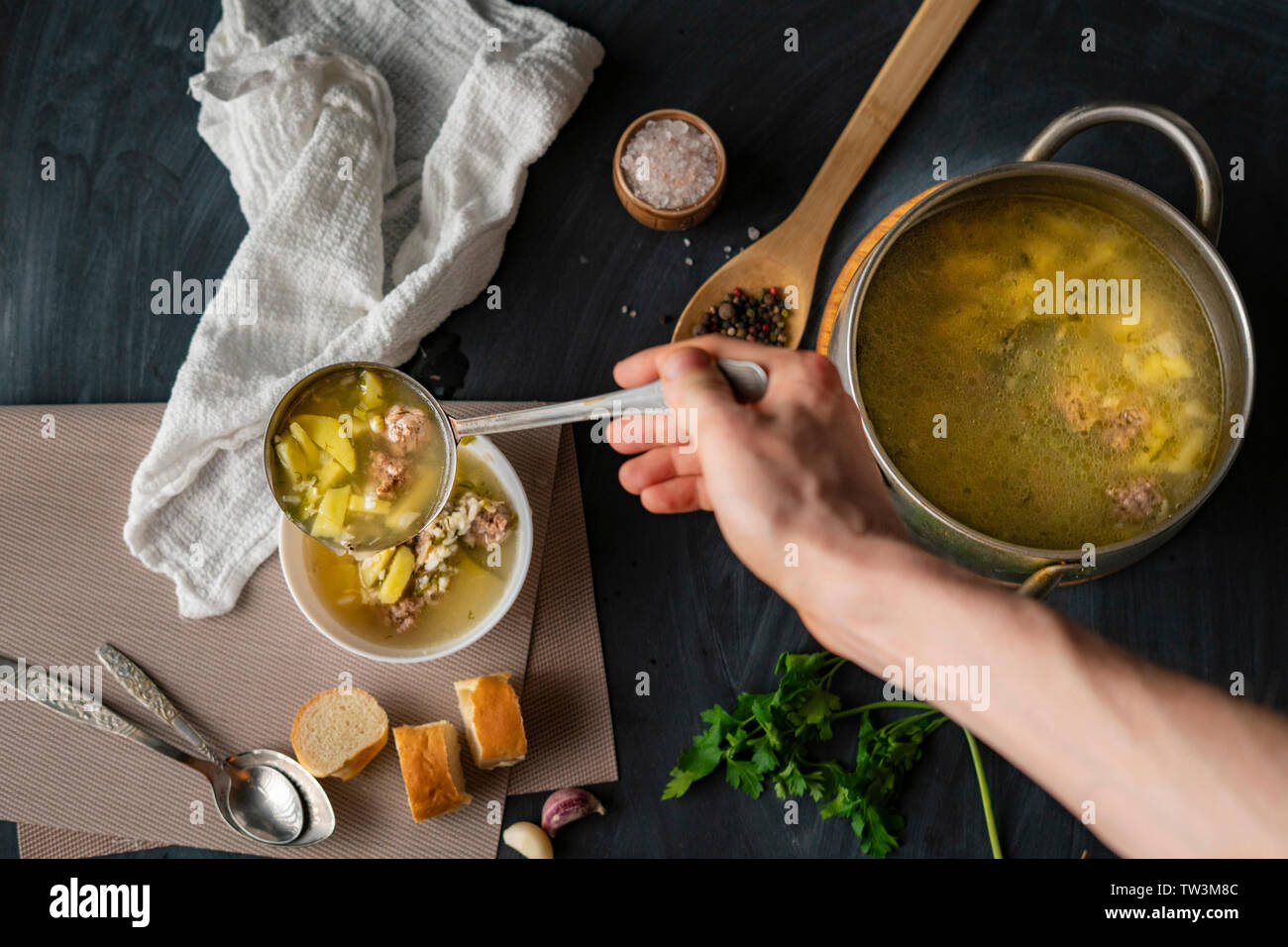 chefs hand pour fresh hot soup in a white empty bowl, food preparation ...