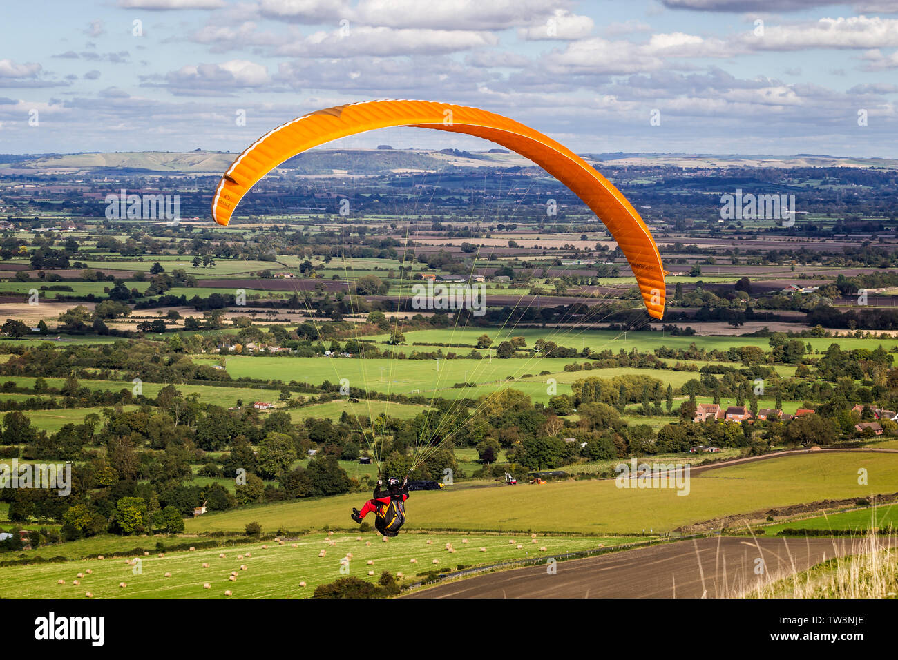 Paraglider with yellow parachute gliding over green landscape Stock ...