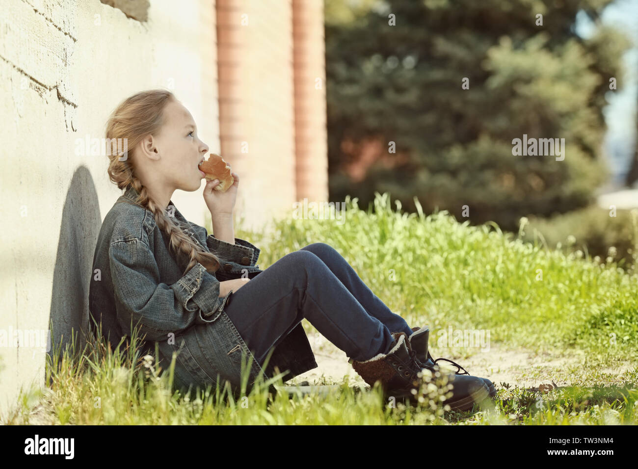 Poor little girl eating bread outdoors Stock Photo - Alamy