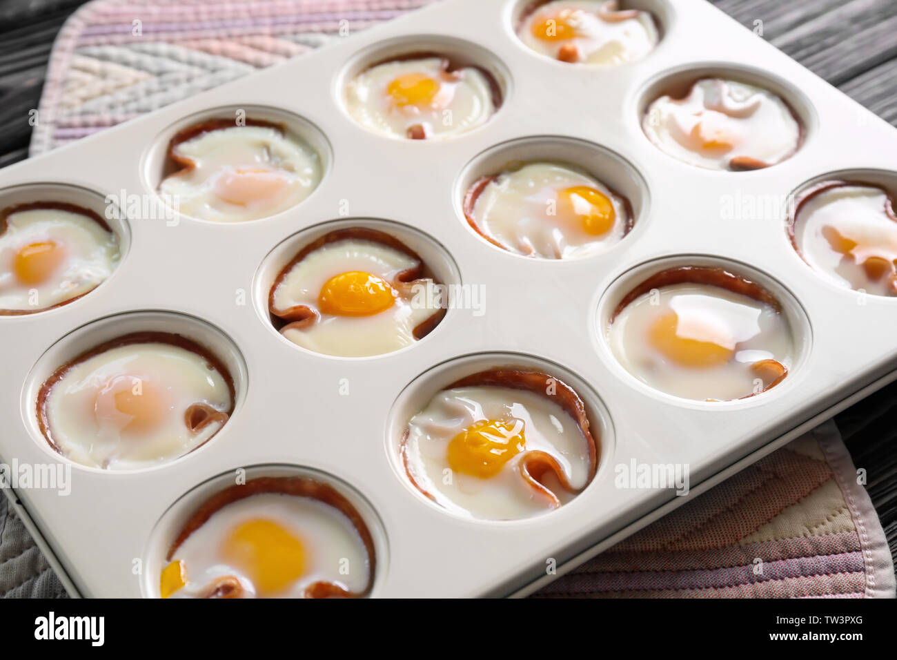 Baking mold with tasty eggs and ham on table Stock Photo - Alamy