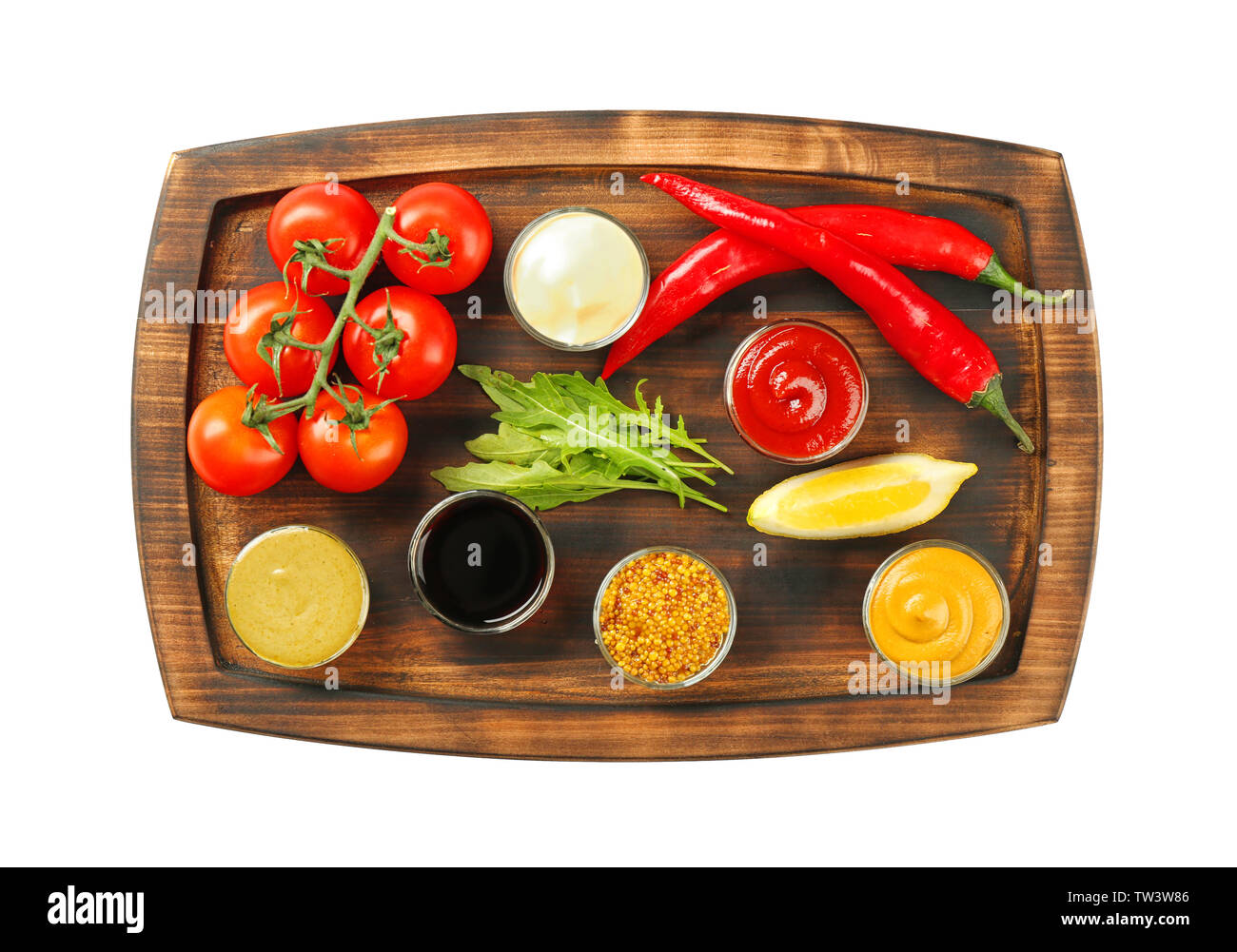 Wooden plate with different sauces and vegetables on white background ...