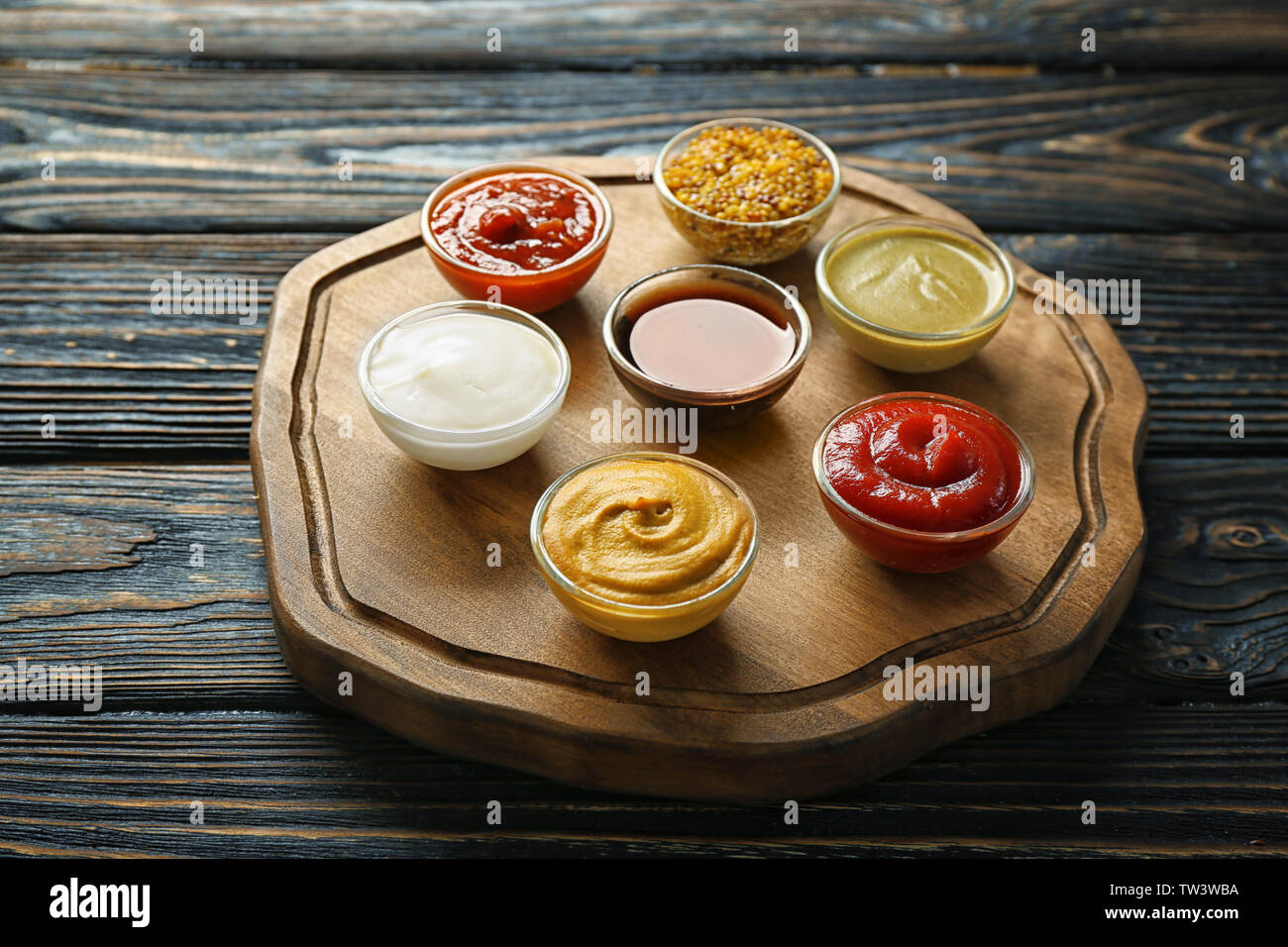 Wooden plate with different sauces on table Stock Photo - Alamy