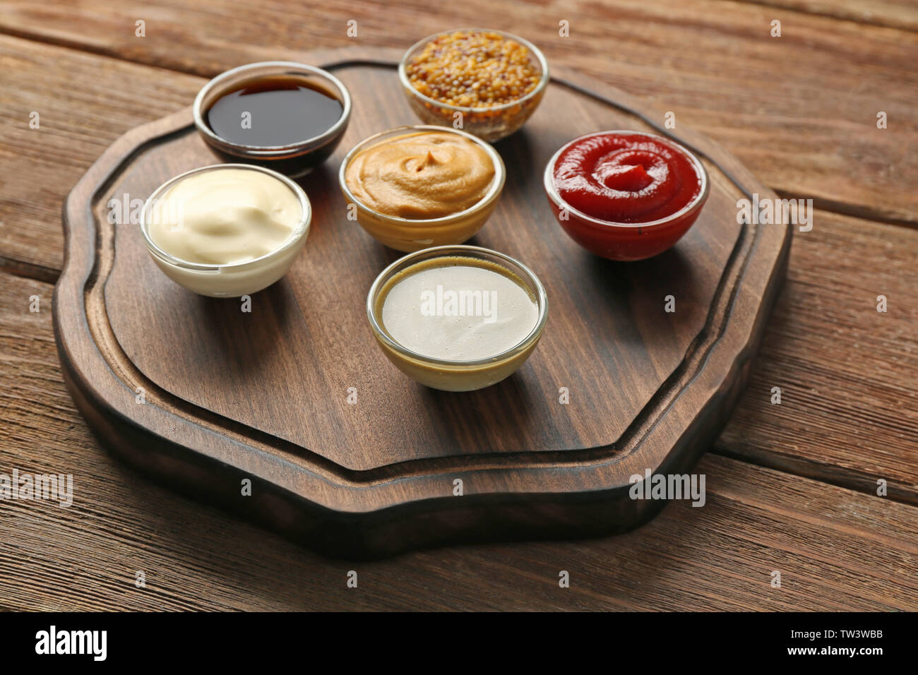 Wooden plate with different sauces on table Stock Photo - Alamy