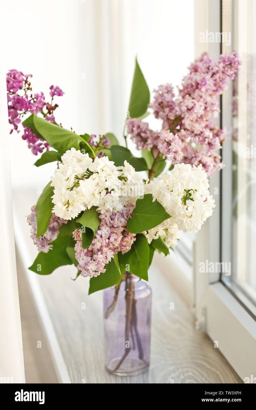 Glass vase with beautiful lilac flowers on window sill Stock Photo - Alamy