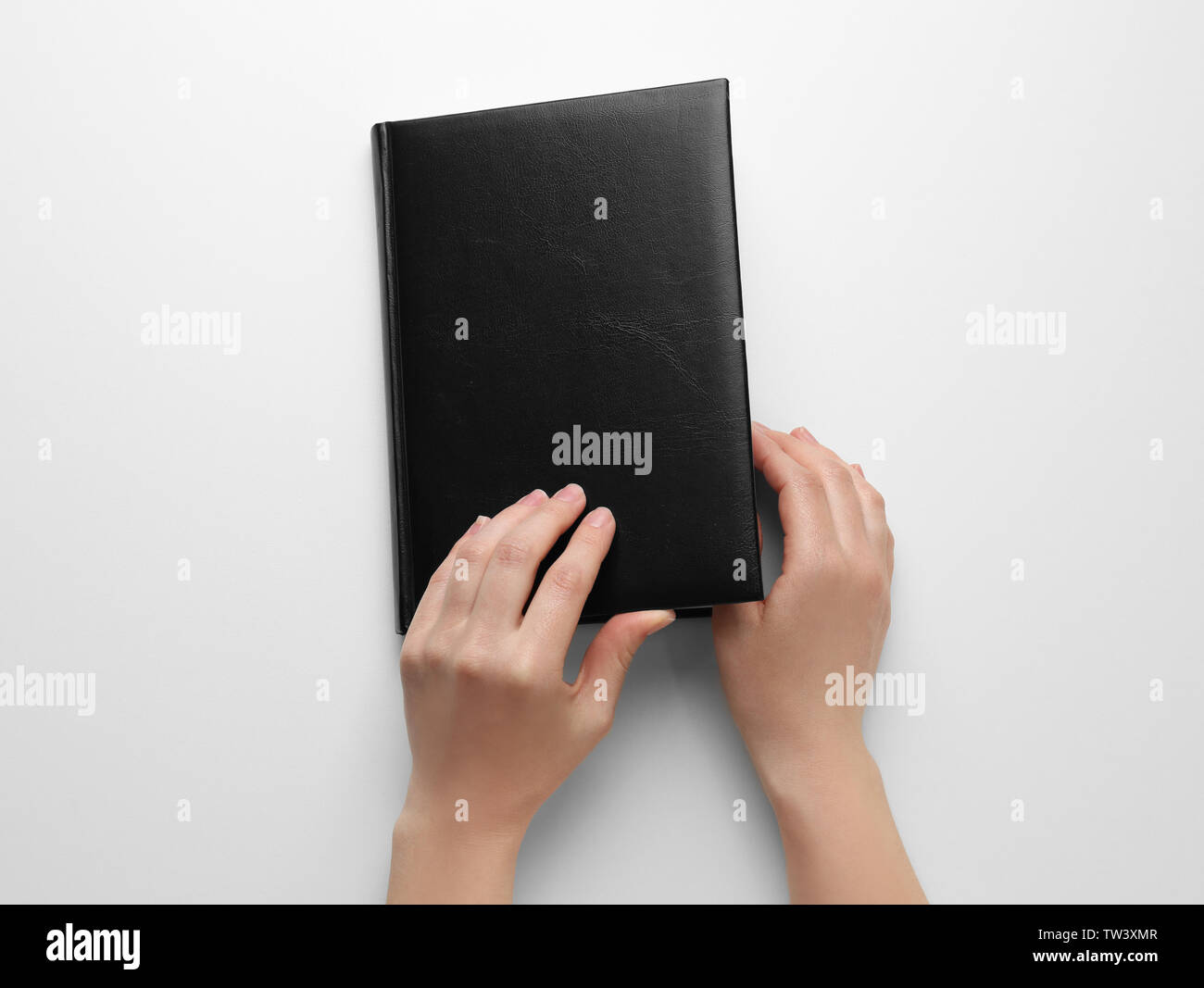 Female hands holding closed book with black blank cover on white ...
