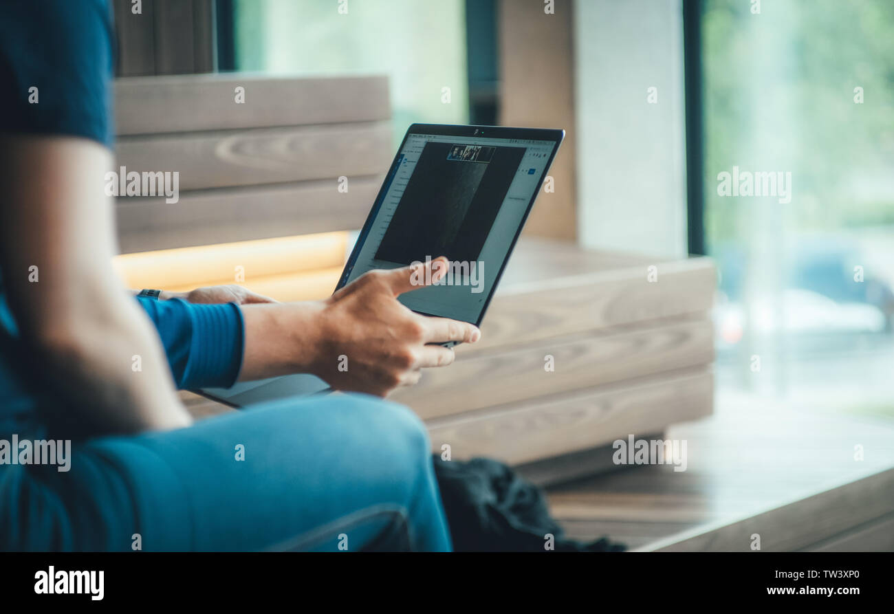 2 people looking at laptop screen, faces hidden. Modern wooden ...