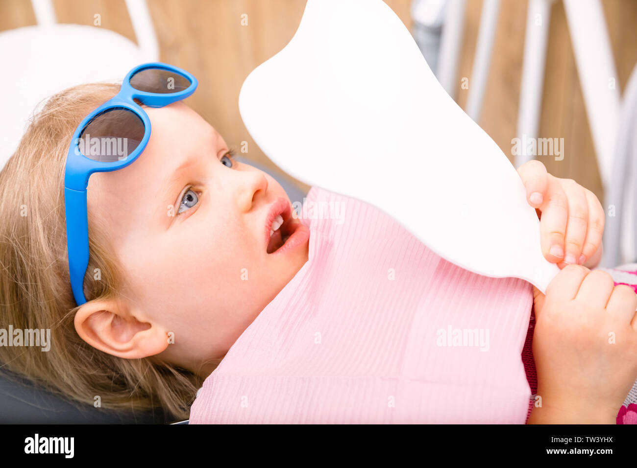 Little girl sitting in a dental chair inspecting her cured teeth ...