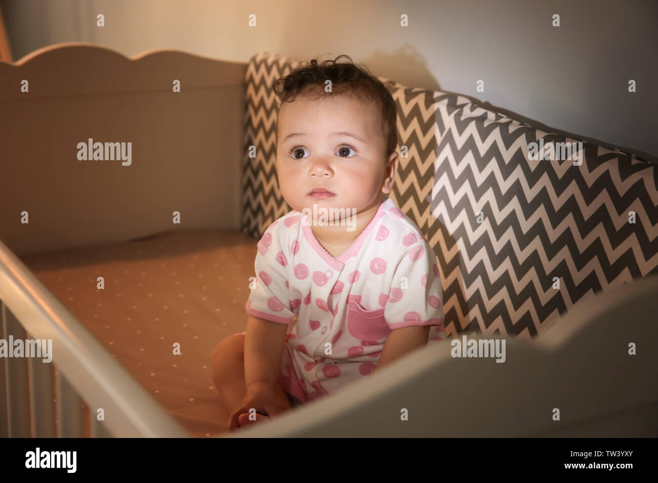 Cute little baby sitting in cradle at home. Sleep disorders concept ...