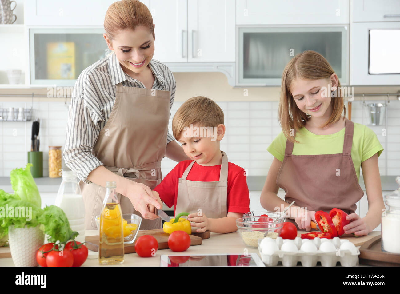 Mother and children making meal together in kitchen. Cooking classes ...