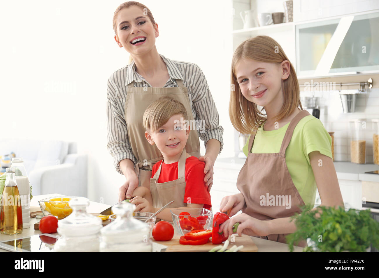 Mother and children making meal together in kitchen. Cooking classes ...