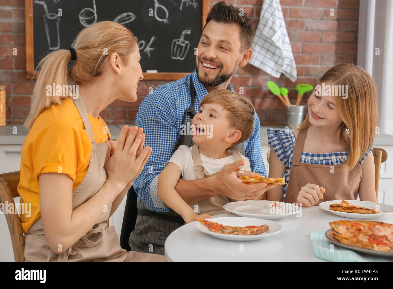 Family eating yummy pizza together in kitchen. Cooking classes concept ...