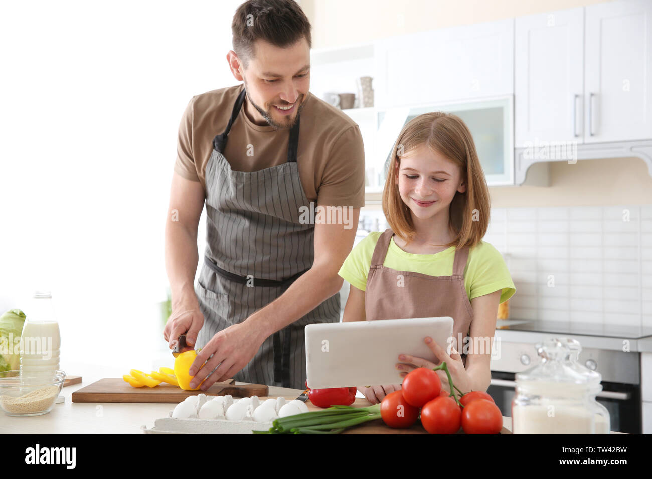 Father and daughter making meal together in kitchen. Cooking classes ...