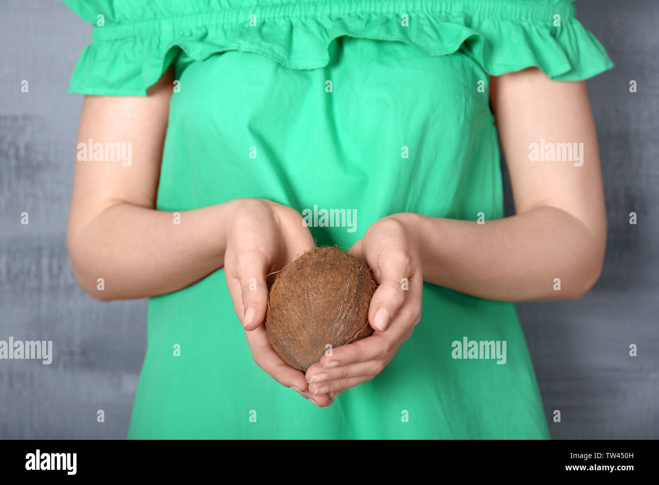 Young woman with coconut on grey background Stock Photo - Alamy