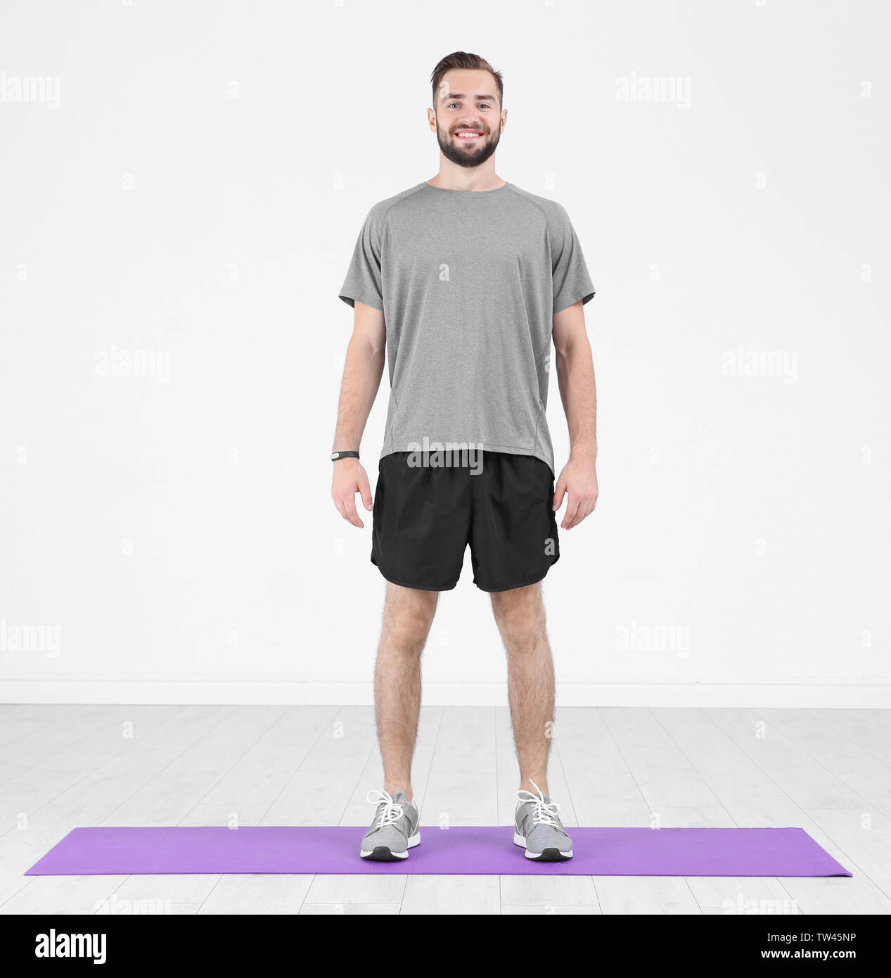 Sporty young man standing on mat in gym Stock Photo - Alamy