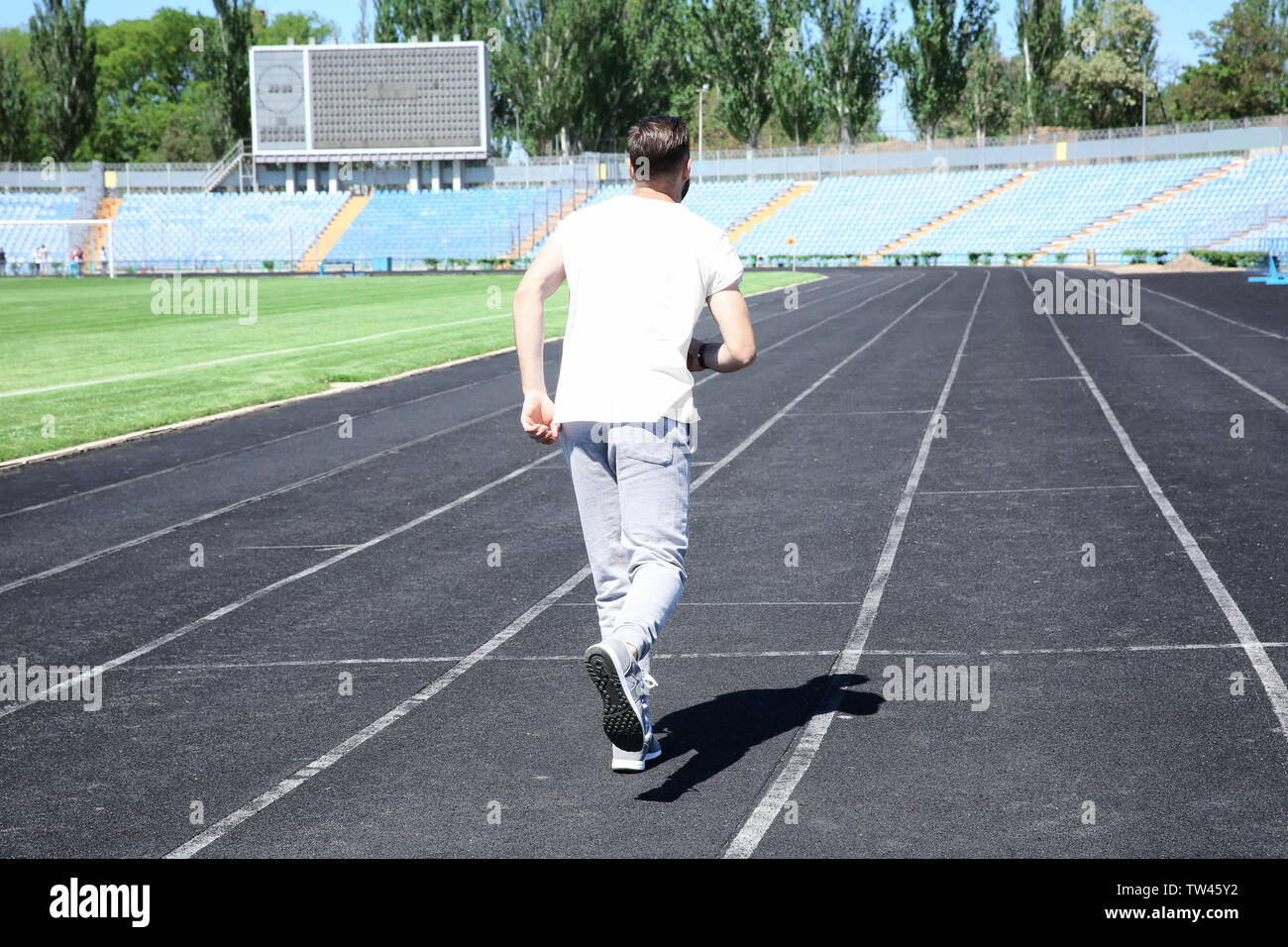 Sporty young man running at stadium Stock Photo - Alamy