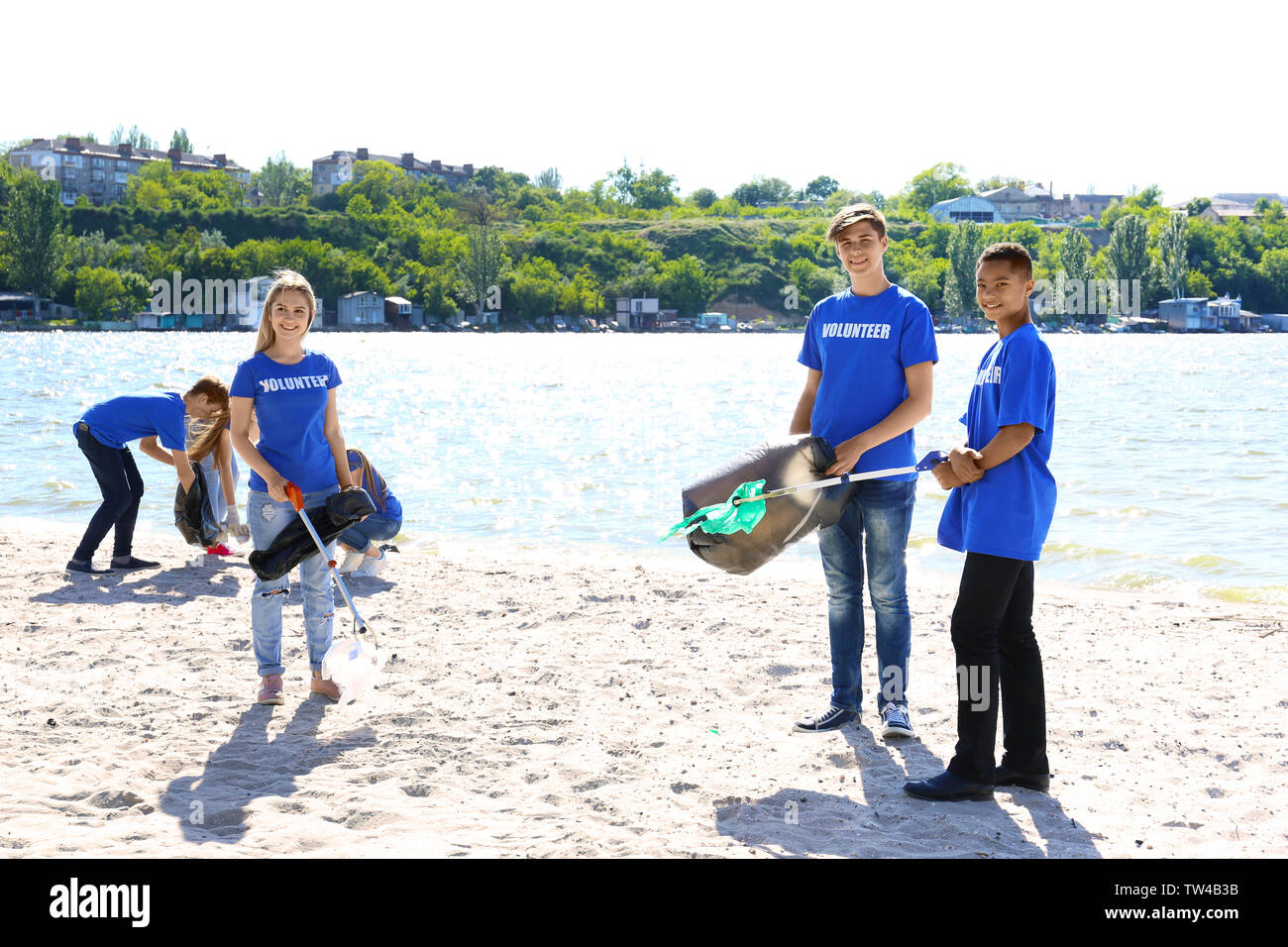 Group of young people cleaning beach area. Volunteer concept Stock ...