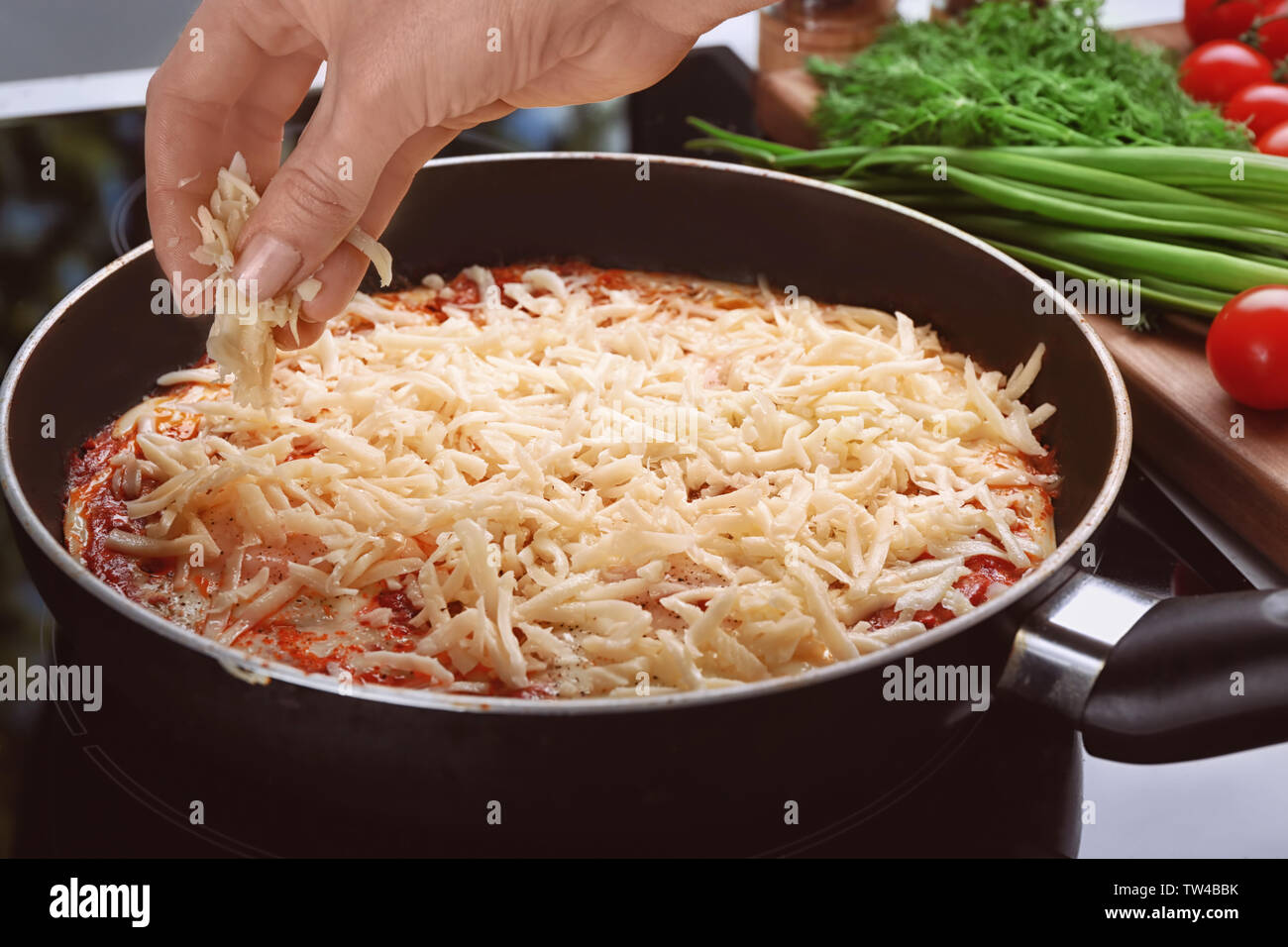 Woman pouring cheese on eggs in purgatory Stock Photo - Alamy