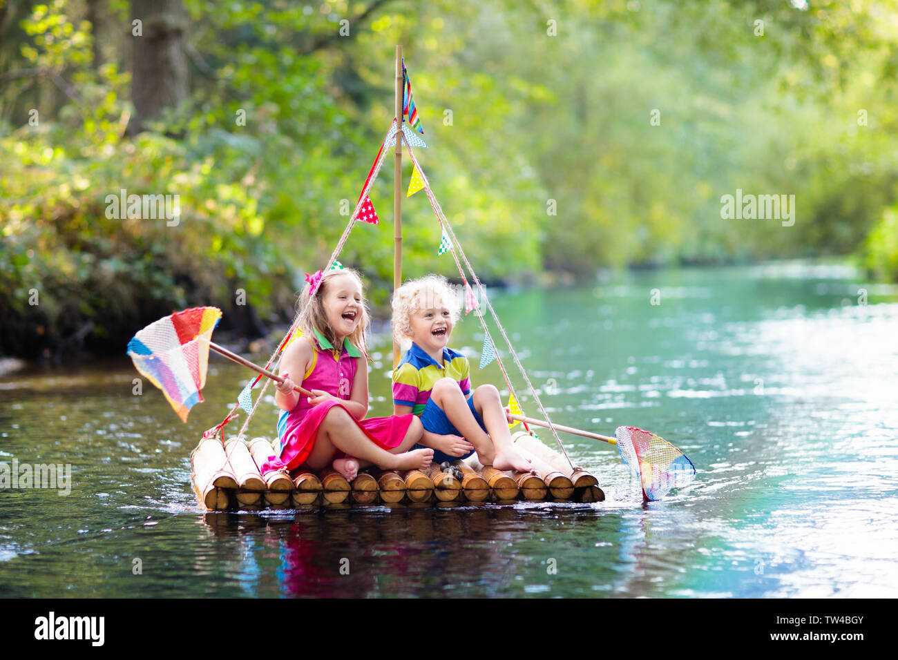 Two children on wooden raft catching fish with a colorful net in a ...